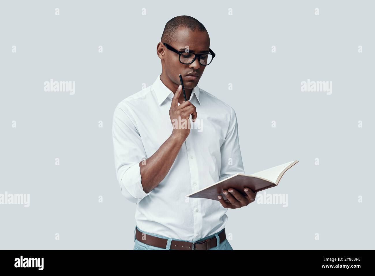 Student. Handsome young African man reading something while standing ...