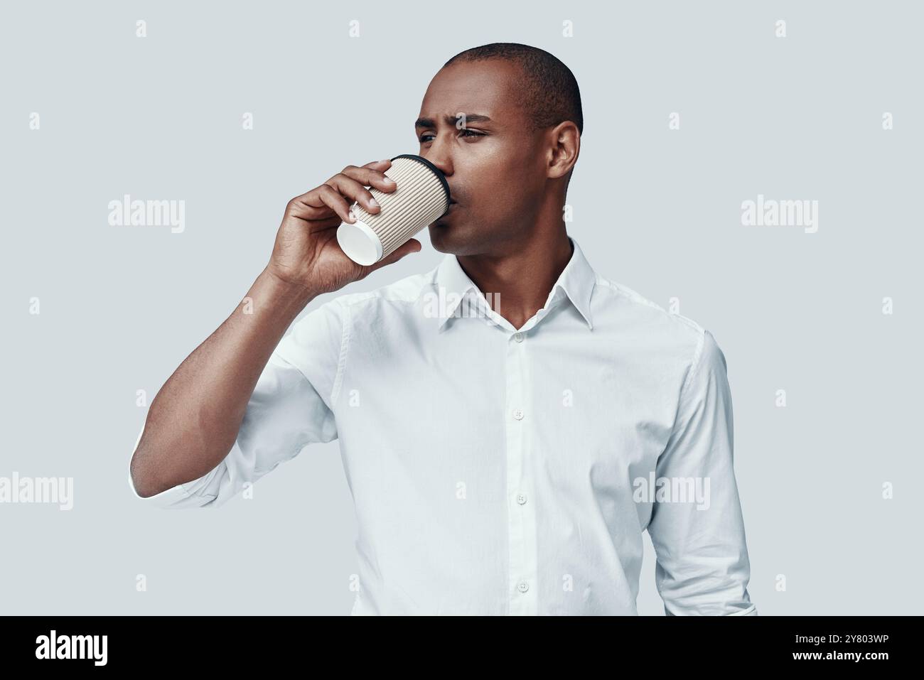 Morning coffee. Handsome young African man drinking coffee while ...