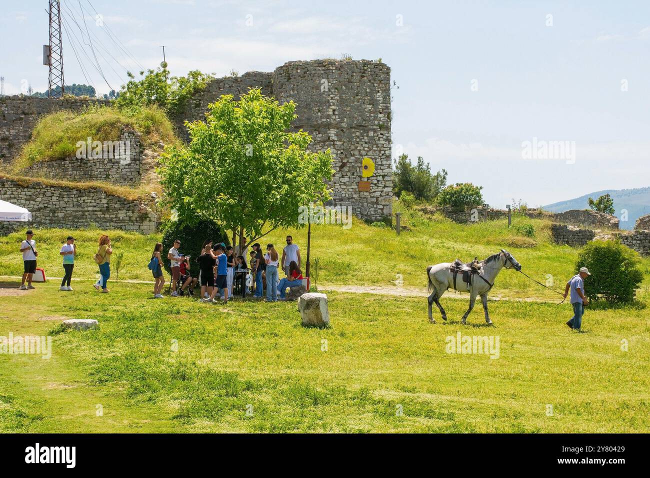 Berat, Albania - June 2nd 2024. Visitors gather in the shade in the ...