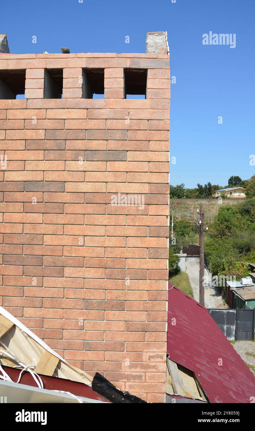 A close-up on roofing construction with brick chimney waterproofing in ...