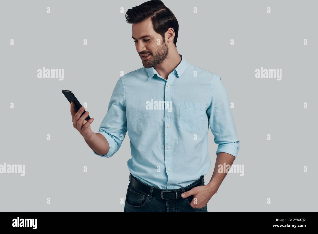 Receiving messages from friends. Handsome young man using smart phone ...