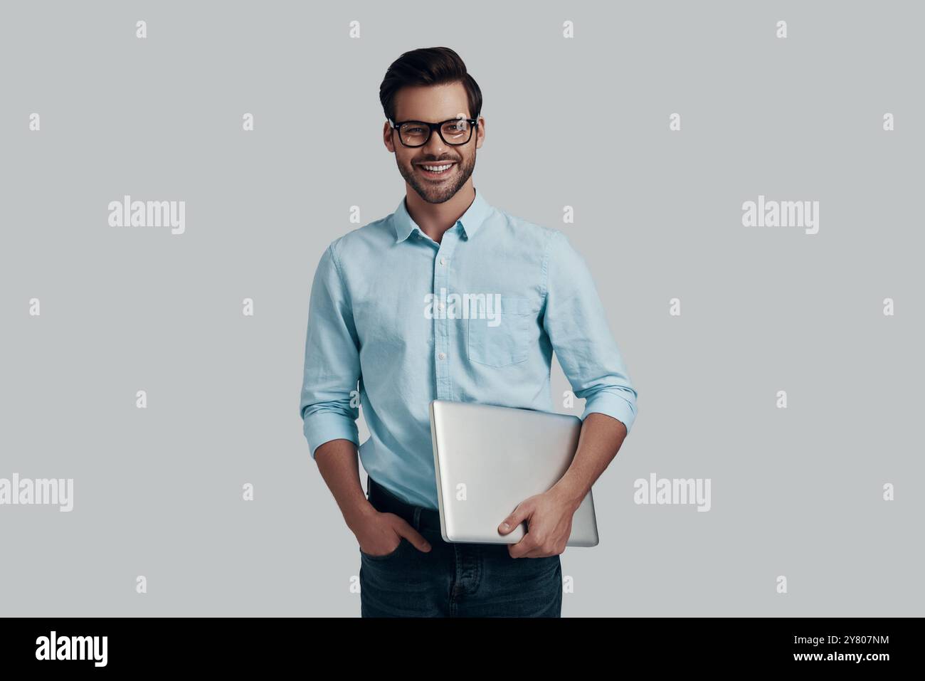 Happy businessman. Handsome young man carrying laptop and looking at ...