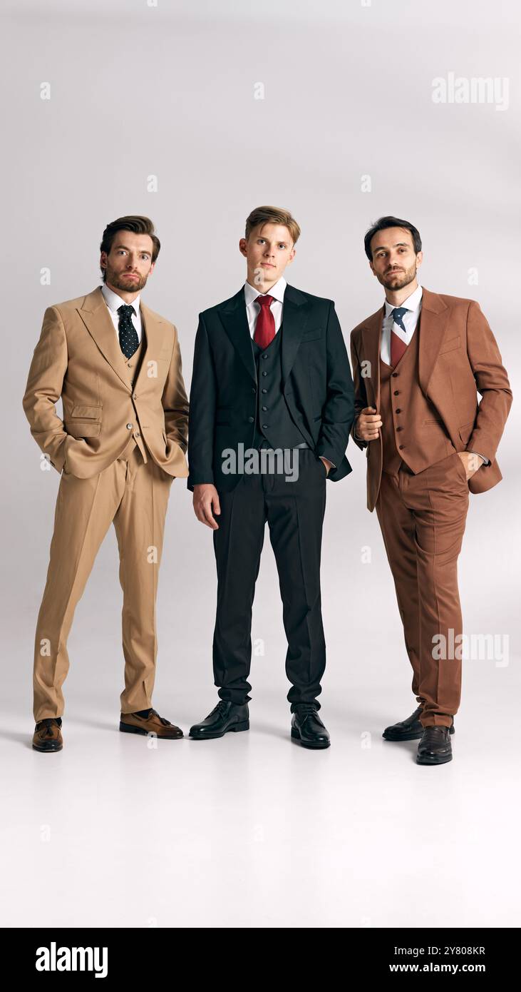 Three elegant men, dressed sandy style suits posing, showing confidence ...