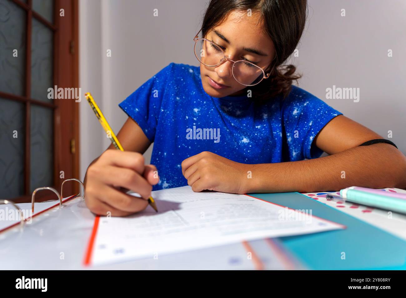 Young Girl Focused on Homework, Writing in Notebook at Study Desk Stock ...
