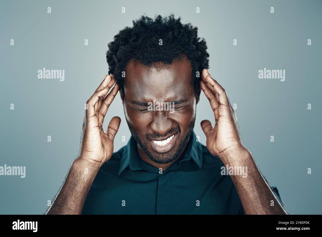 Frustrated young African man making a face while standing against grey ...