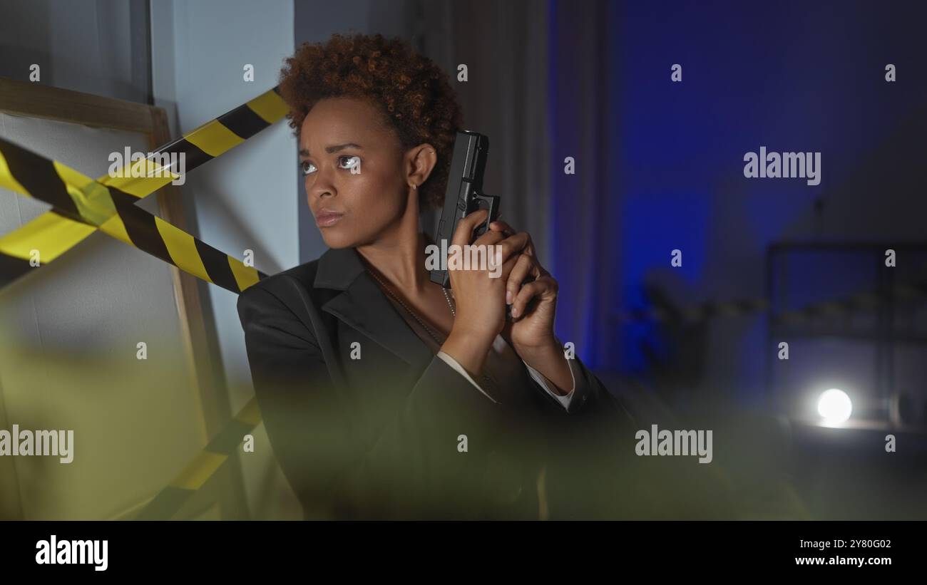 African american woman detective with gun at night-time indoor crime ...
