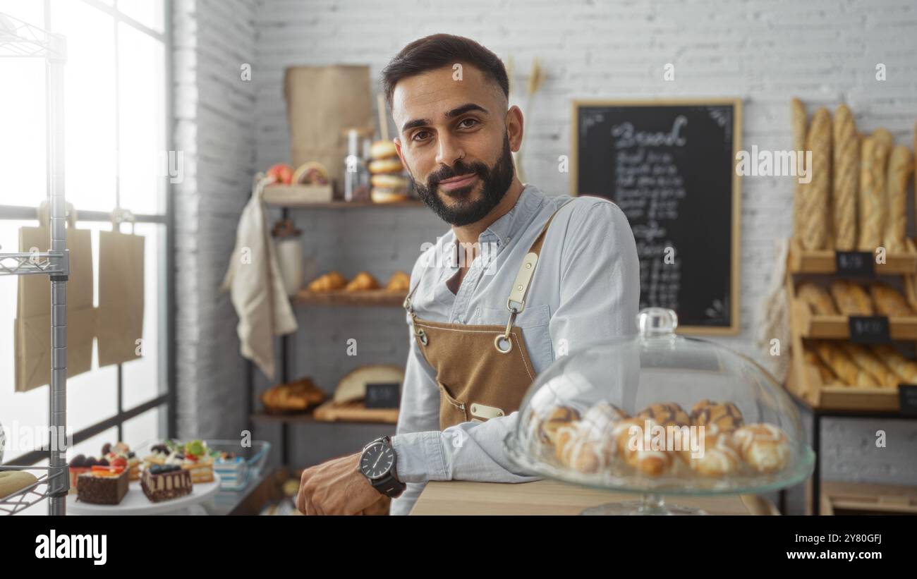 Young hispanic man with a beard smiling inside a bakery shop interior ...