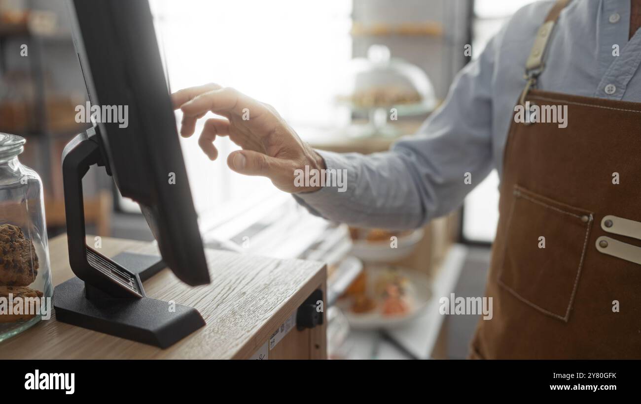 Young man working in a bakery shop, focused on the cash register ...