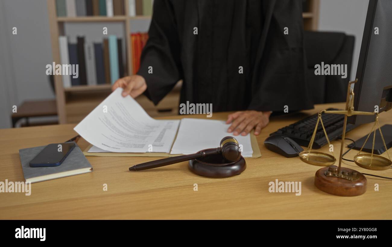 Judge wearing robes reviewing documents in an office with gavel and ...