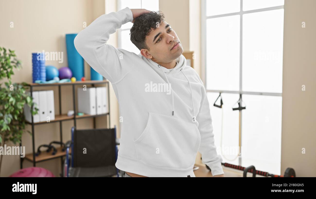 A handsome man stretching in a well-equipped physiotherapy center with ...