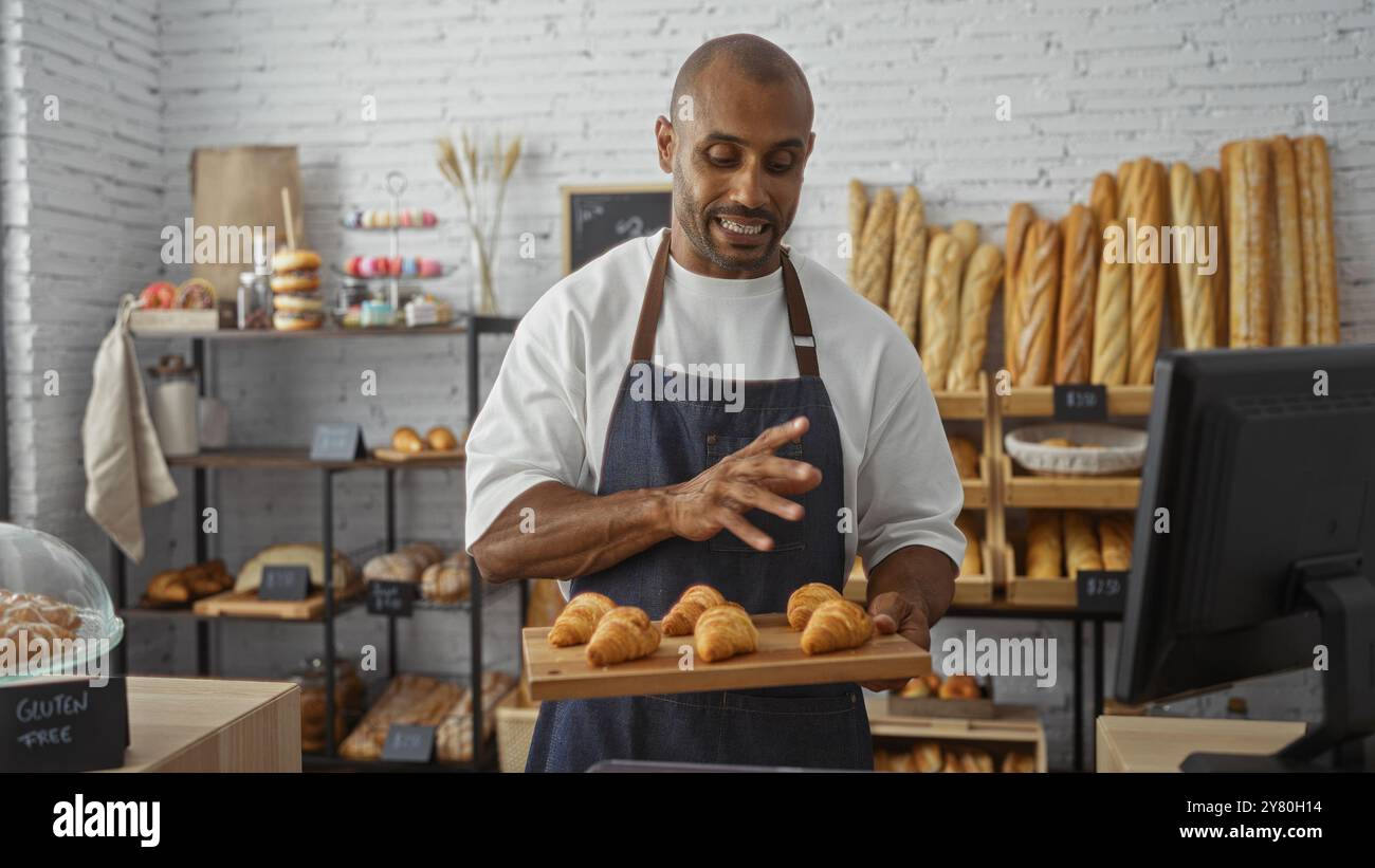 Handsome young african american man holding tray of croissants in ...