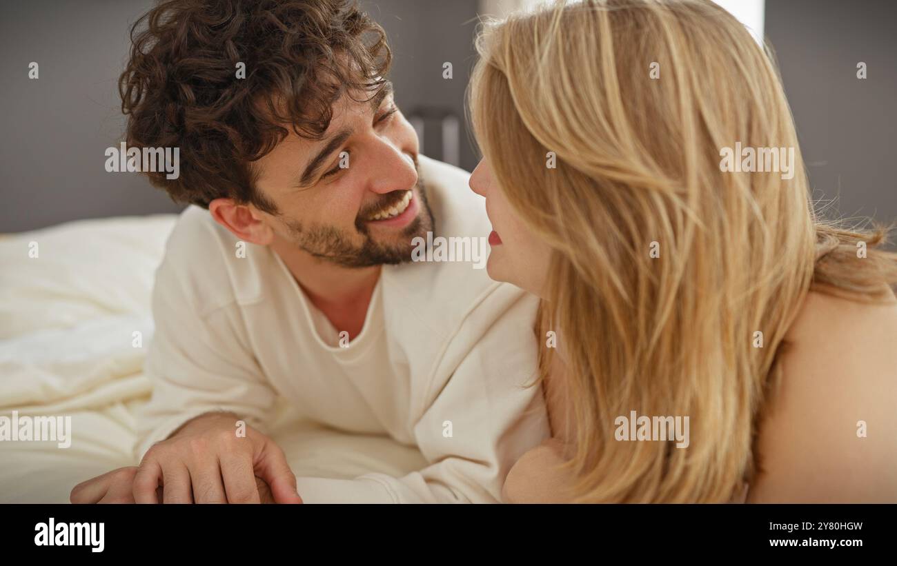 A smiling man and woman lying together on a bed, representing love and ...