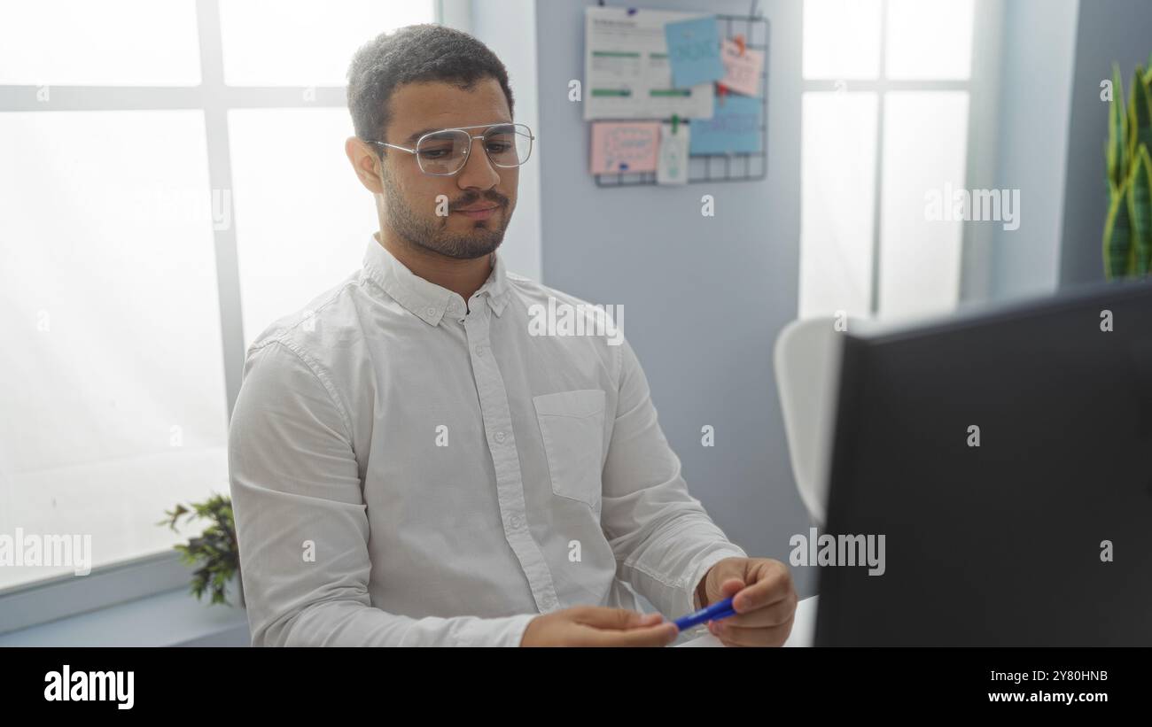 Young man working in an office setting, focusing intently on his task ...