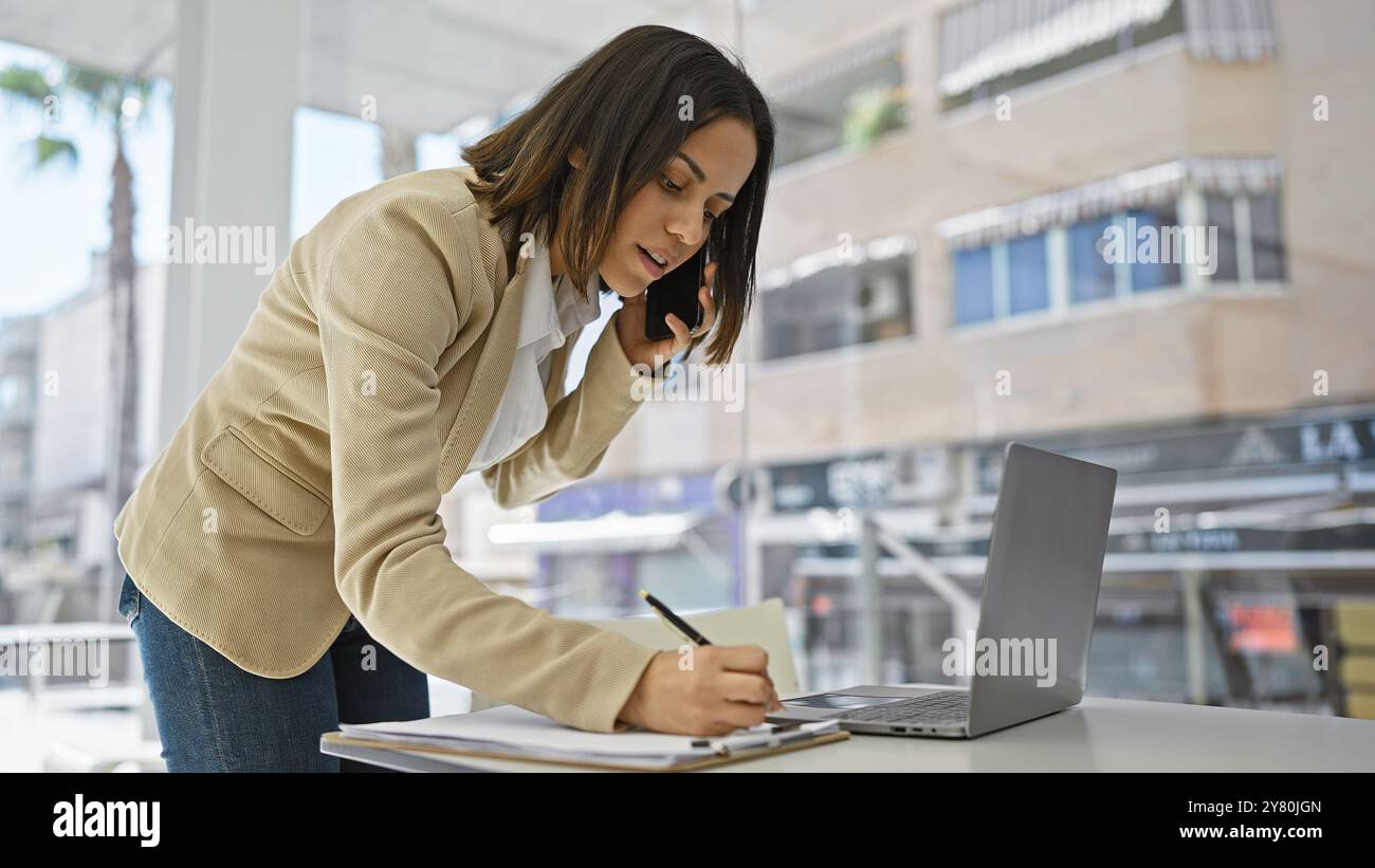 A professional hispanic woman multitasks with a phone call and ...