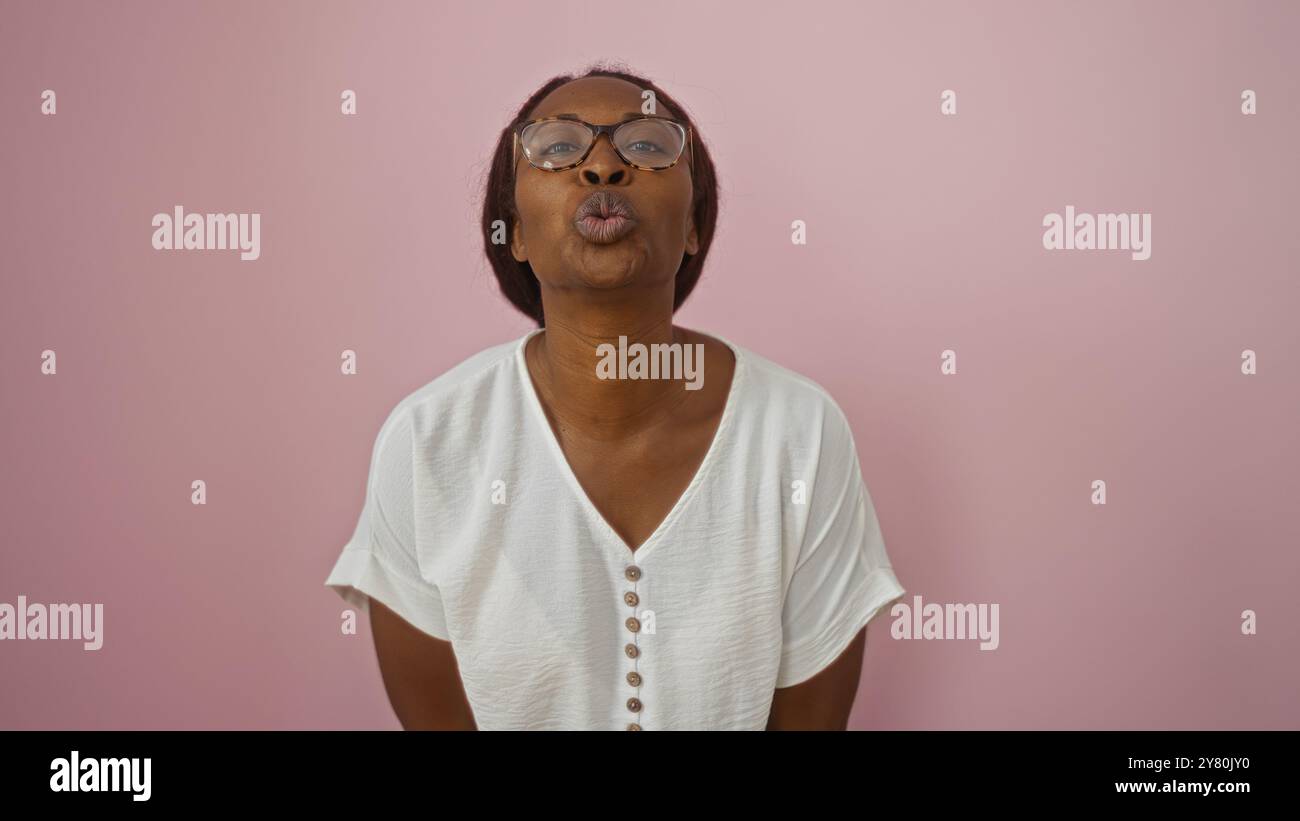 Woman wearing glasses making a kissy face over an isolated pink ...
