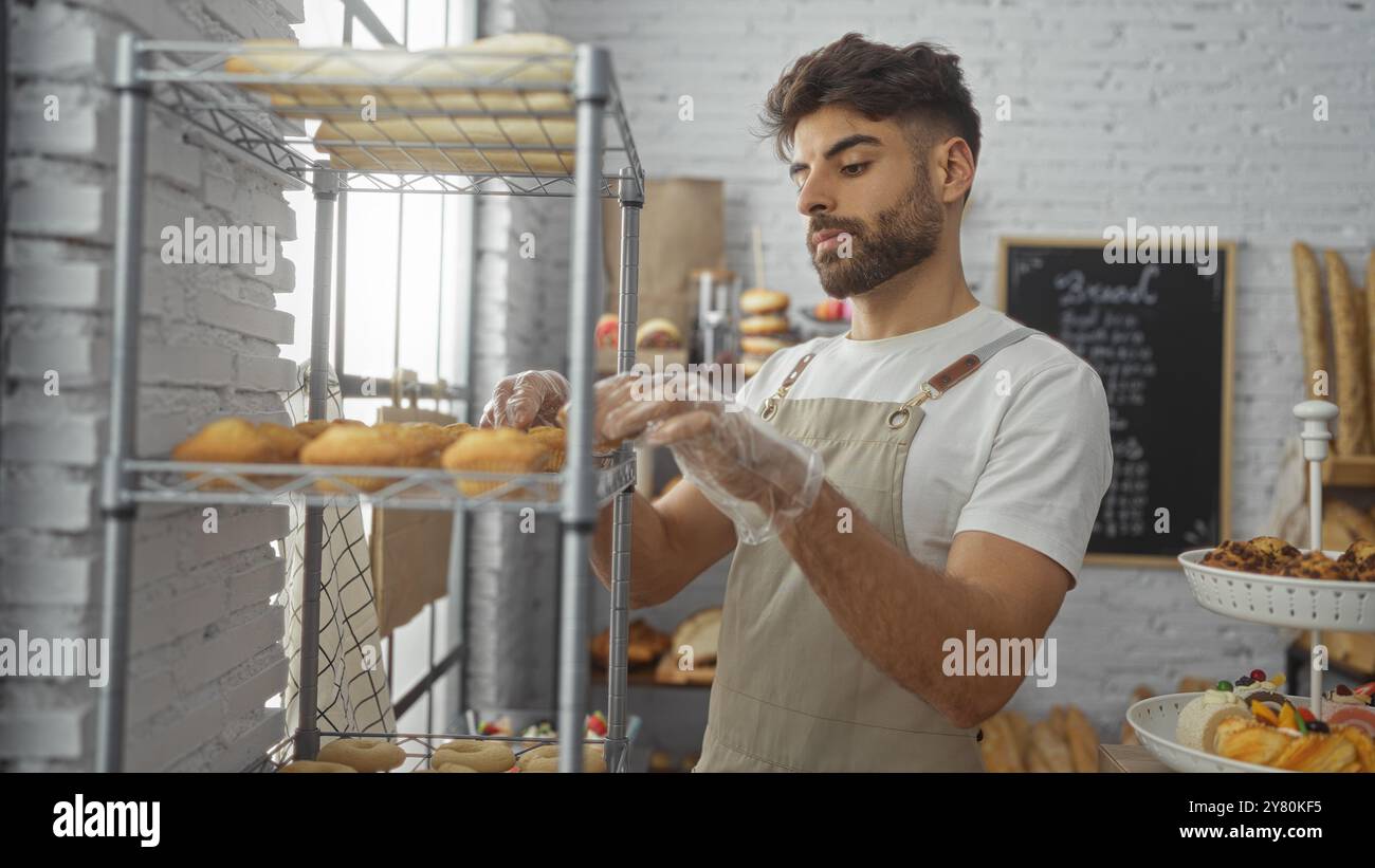 Young hispanic man with a beard wearing an apron and gloves arranging ...