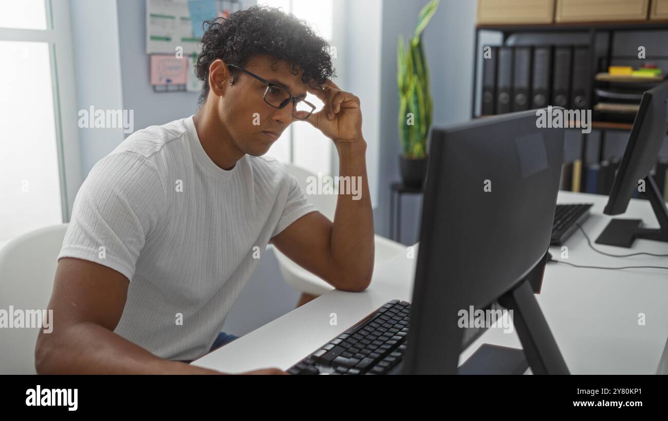 Hispanic man working at computer in modern office, focused and deep in ...