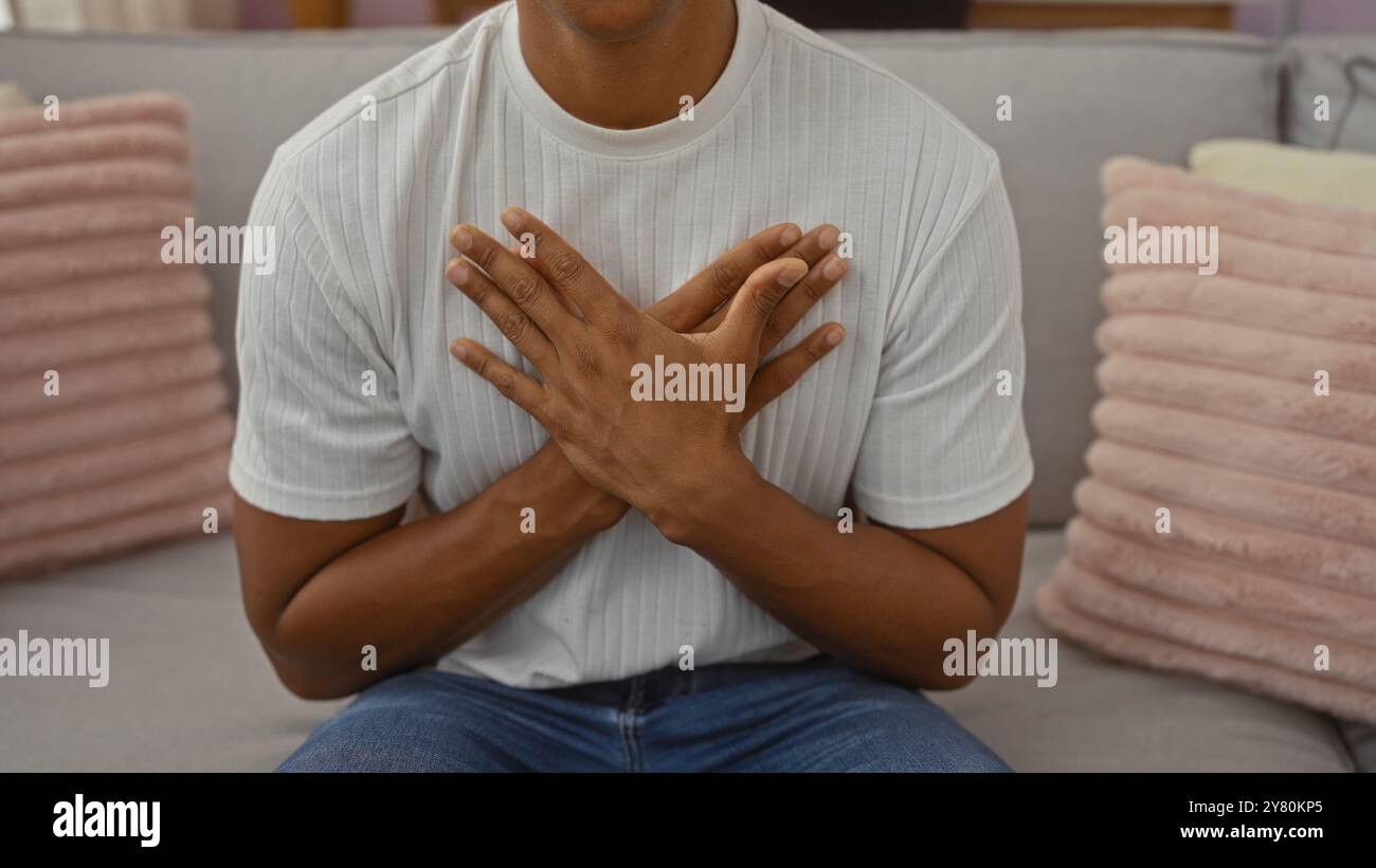 Young man sitting in a living room with hands crossed on his chest, in ...