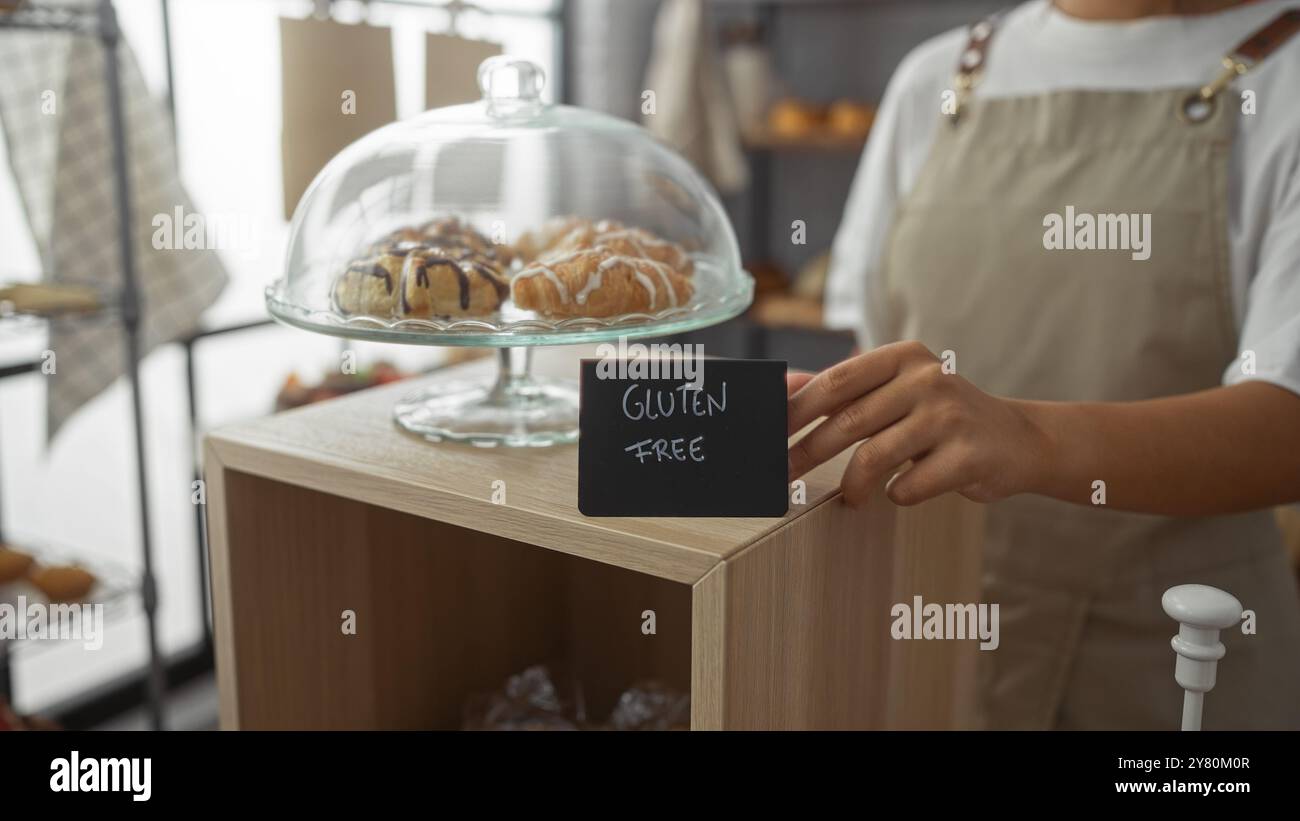 Woman arranging a gluten-free pastry sign in a bakery shop with her ...