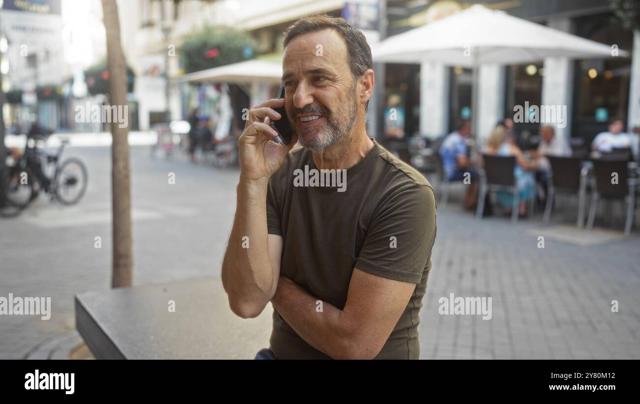 Hispanic man having a phone conversation outdoors in a busy urban city ...