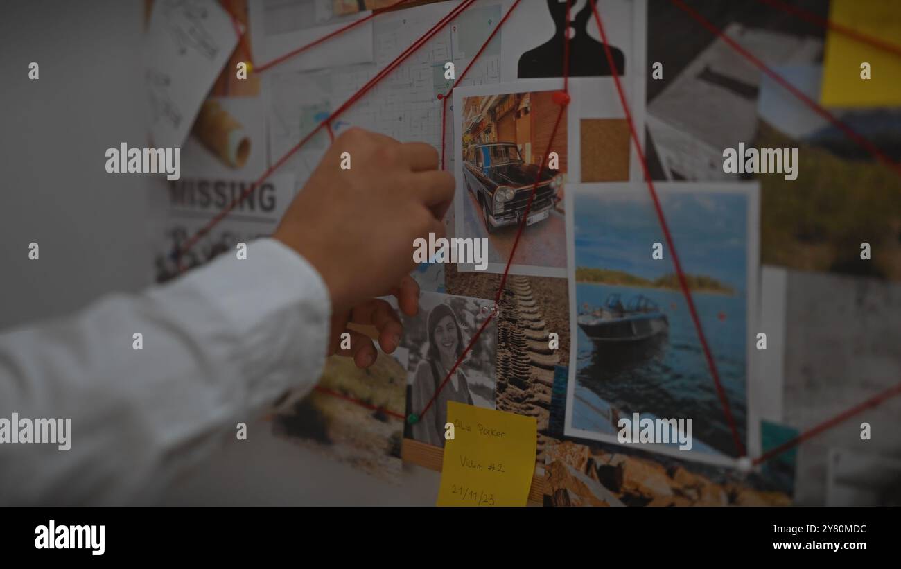 A man analyzes a crime evidence board with photos and notes in a ...