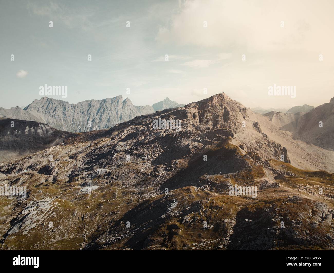 Drone aerial view of the Savognin mountains in Switzerland at sunset, highlighting rugged peaks ...