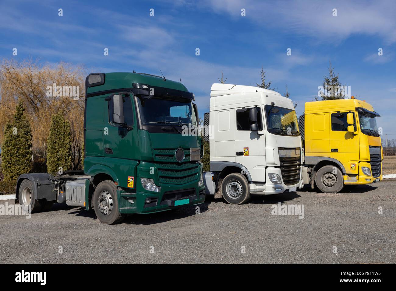 3 trucks parked in a row on a sunny day. cabs of different colors of ...