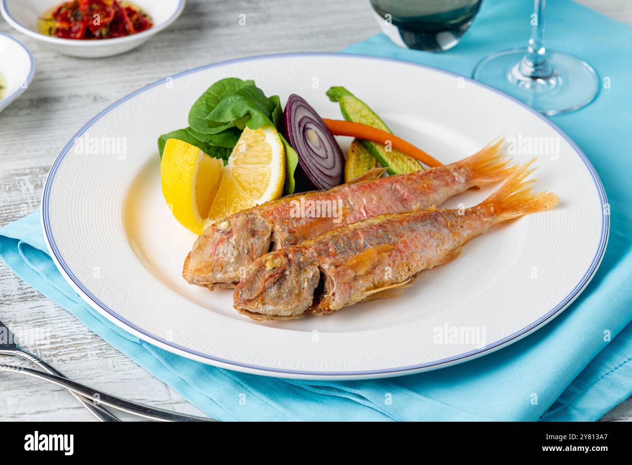 Grilled mullet fish with arugula and mini vegetables on a white ...