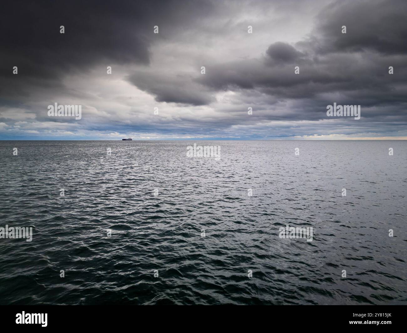 A panoramic view of a vast ocean under a dramatic, overcast sky. A ...