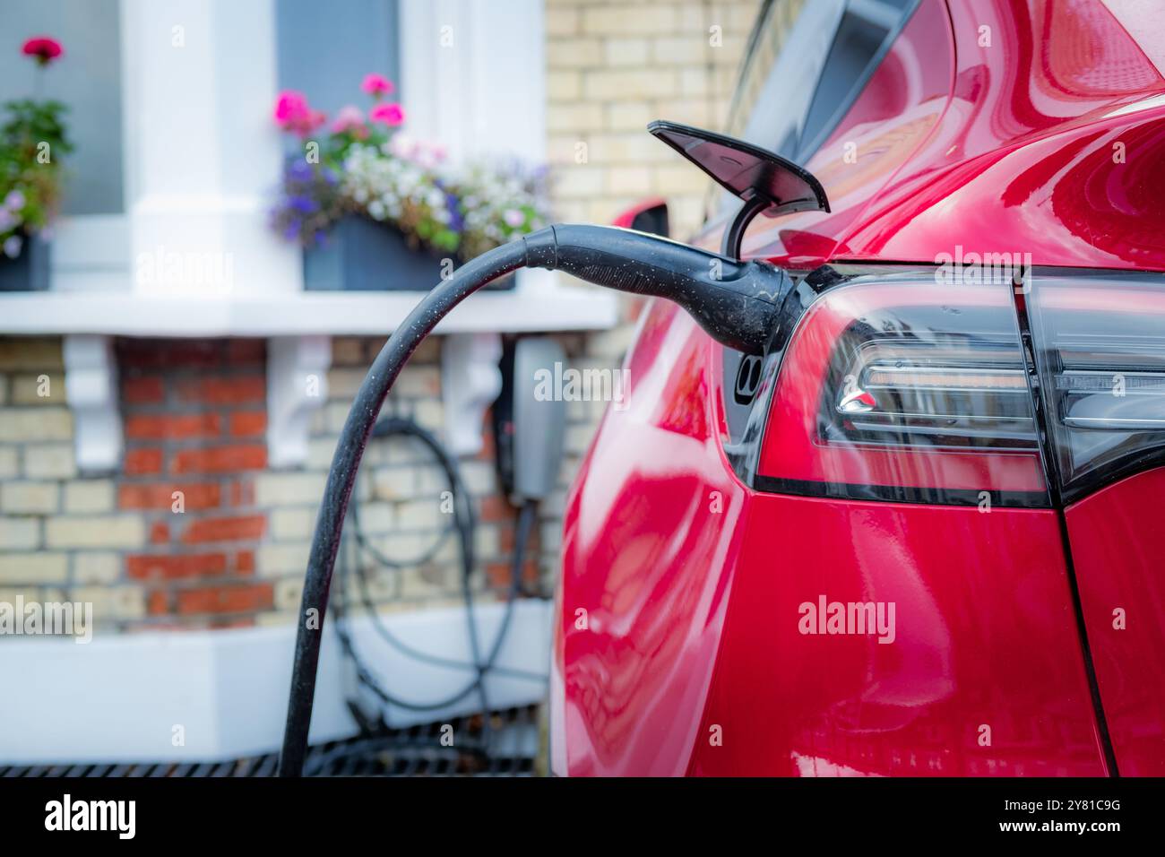 Electric car being charged outside at home in typical British suburban ...