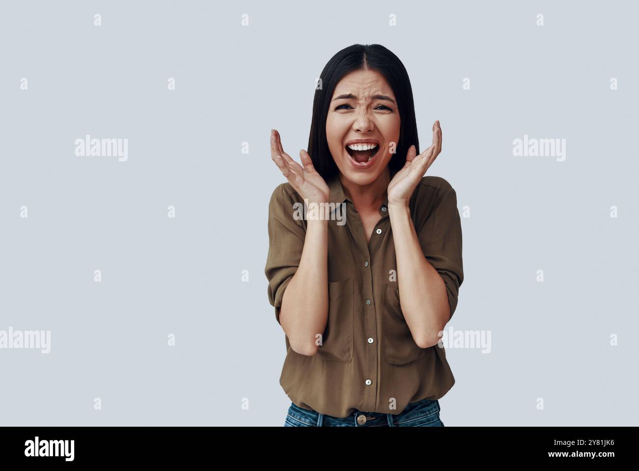 Oh my God! Surprised young Asian woman making a face while standing ...