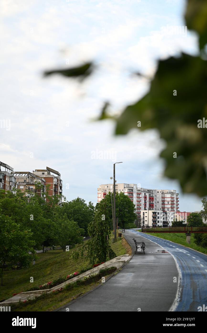 Urban bike path winding through greenery with buildings in the ...