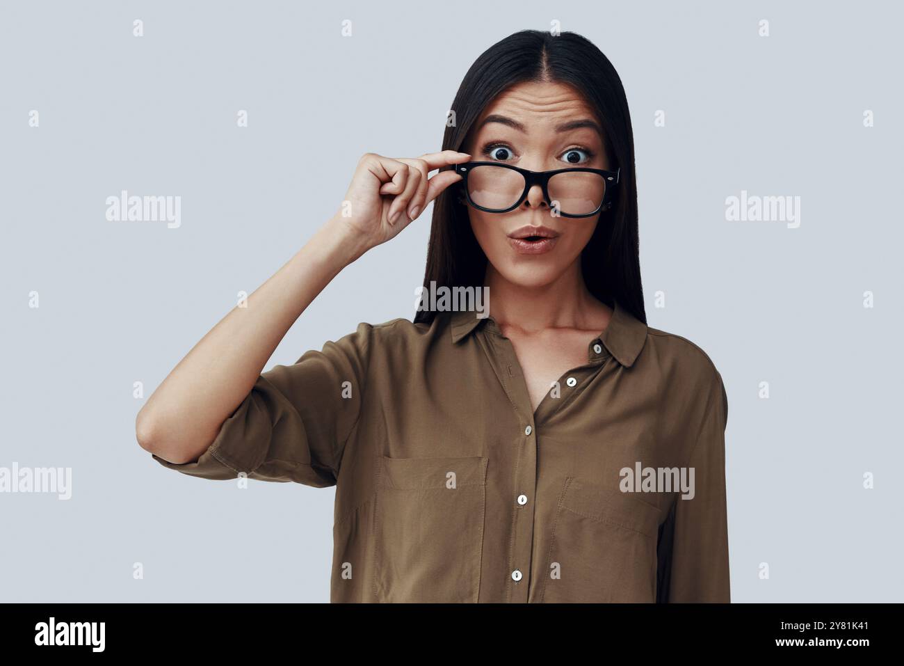Acting silly. Attractive young Asian woman looking at camera and making ...