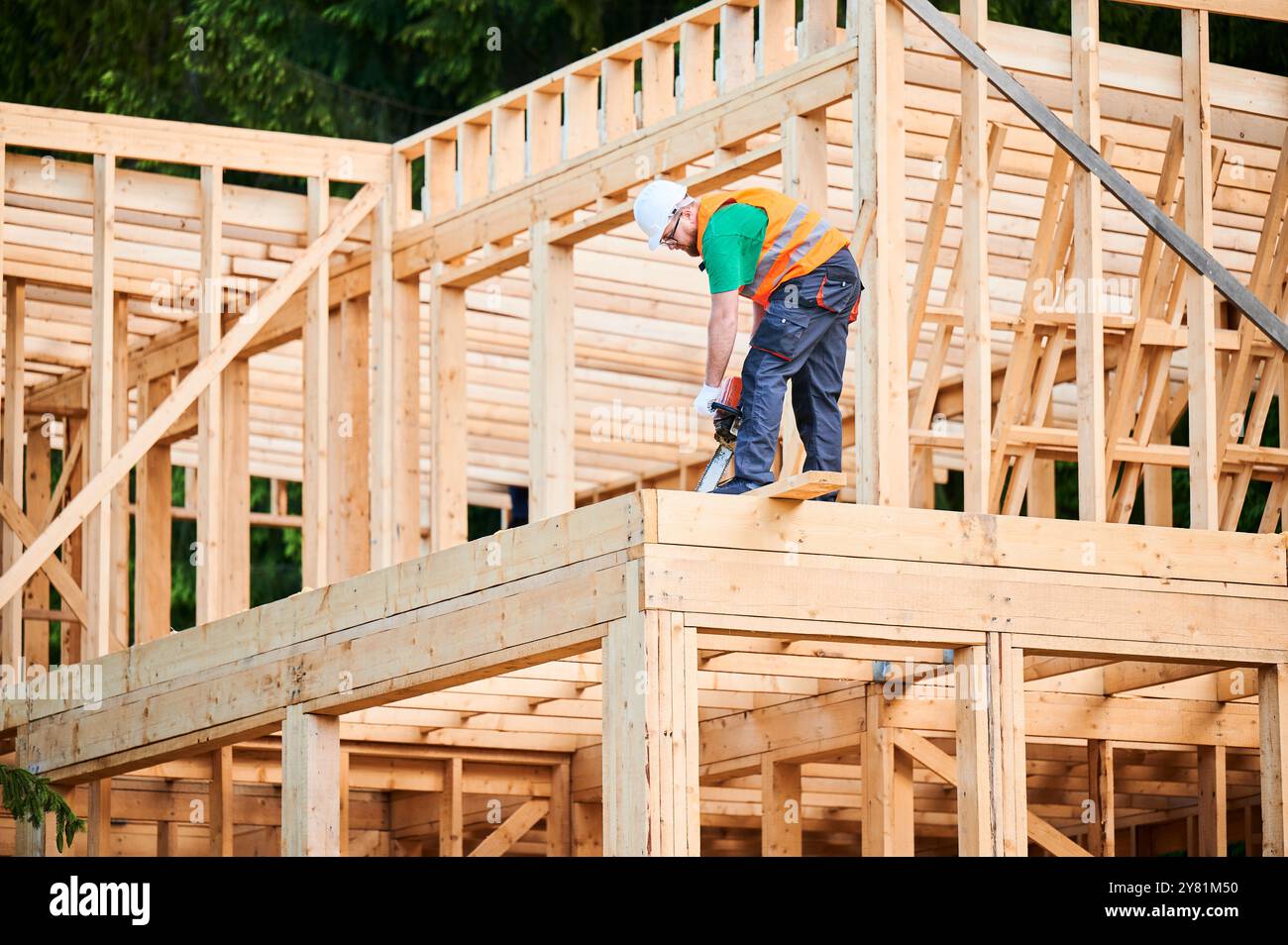 Carpenter using chainsaw for cutting wooden plank. Man worker building ...