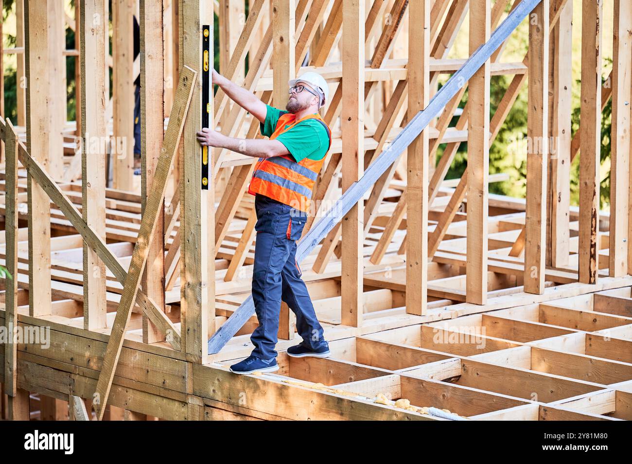 Carpenter constructing two-storey wooden frame house. Man inspects ...