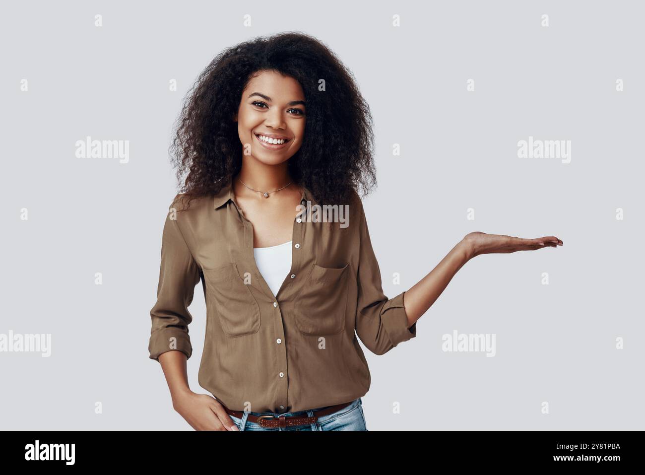 Beautiful young African woman pointing copy space and smiling while ...