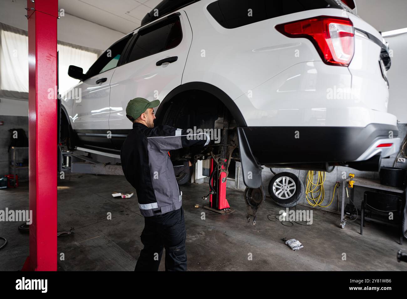 A skilled mechanic in uniform repairing a lifted vehicle in a modern ...