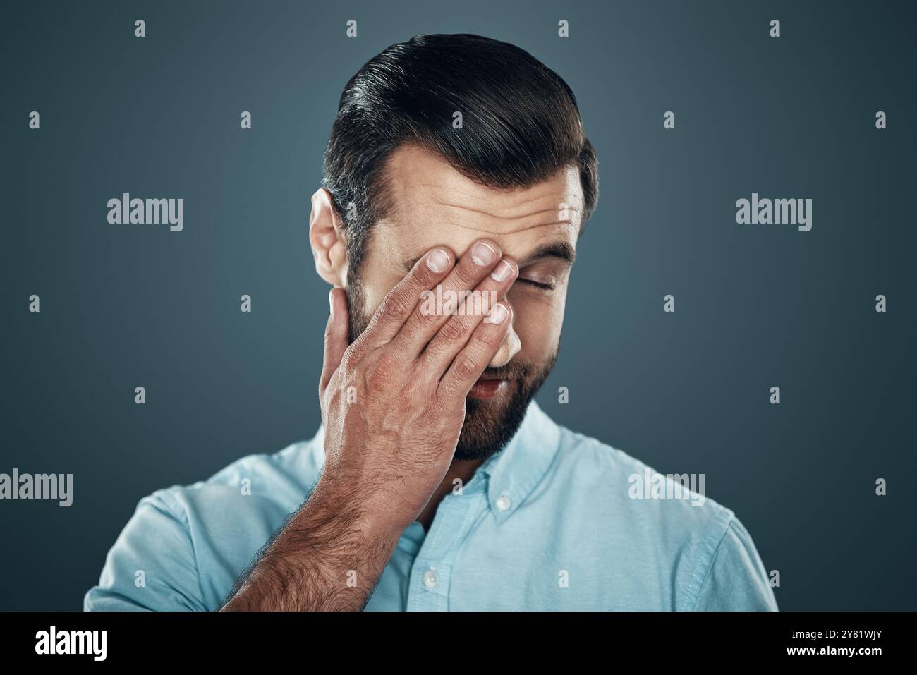 Feeling tired. Handsome young man covering eye with hand and smiling ...