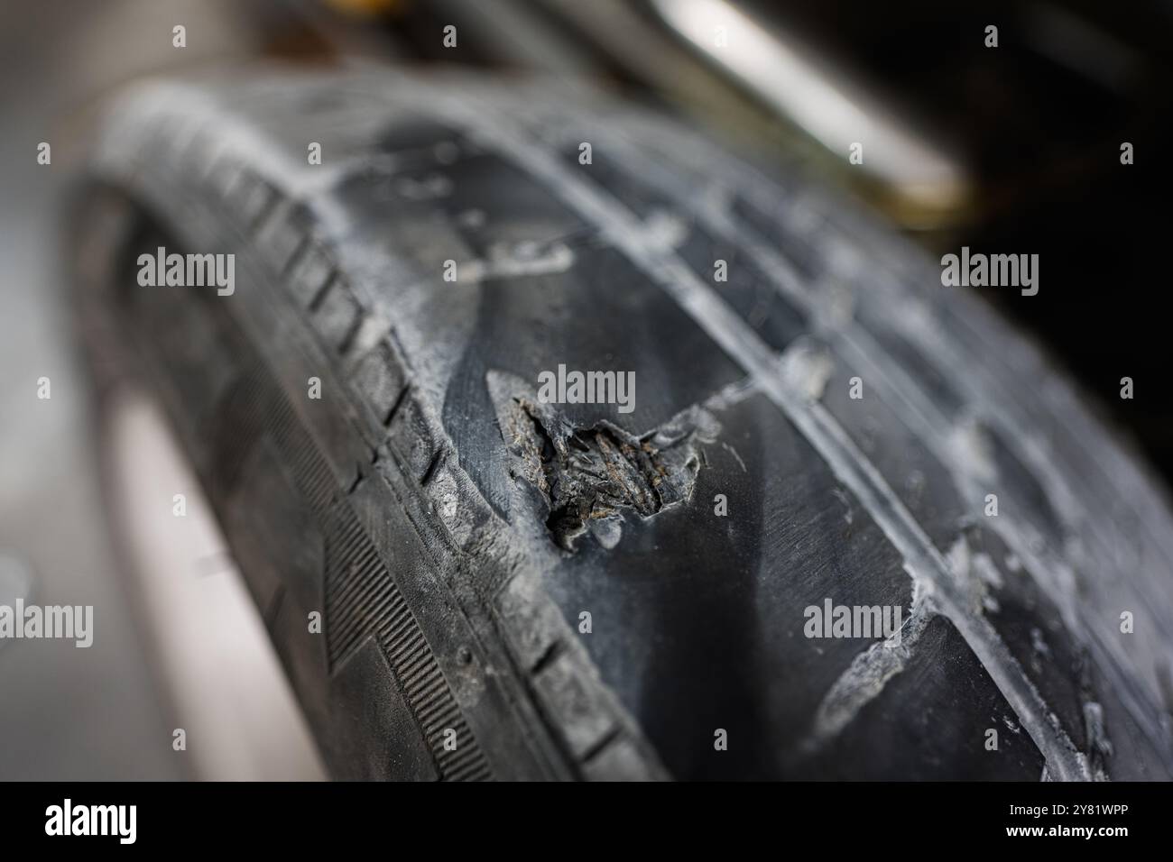 A detailed close-up image of a tire with noticeable damage to the tread ...