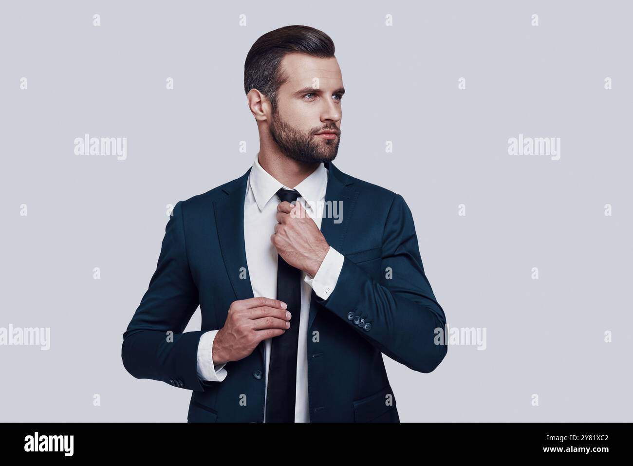 Getting ready to become the best. Handsome young man adjusting necktie ...