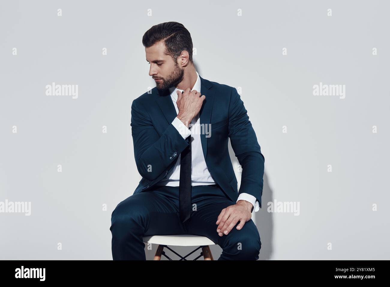Overworked. Handsome young man pulling his collar while sitting against ...