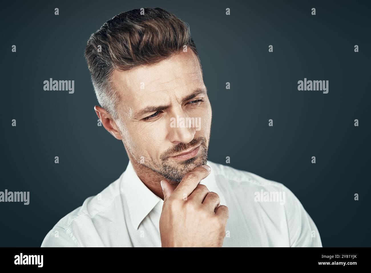 Male beauty. Handsome young man keeping hand on chin and looking away ...
