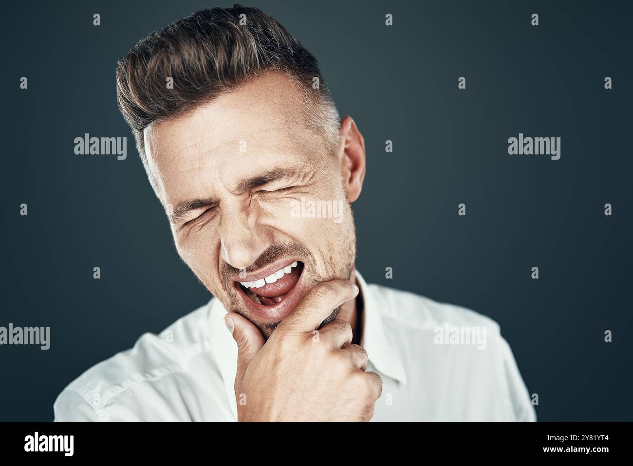 True emotion. Frustrated young man keeping hand on chin and making a ...