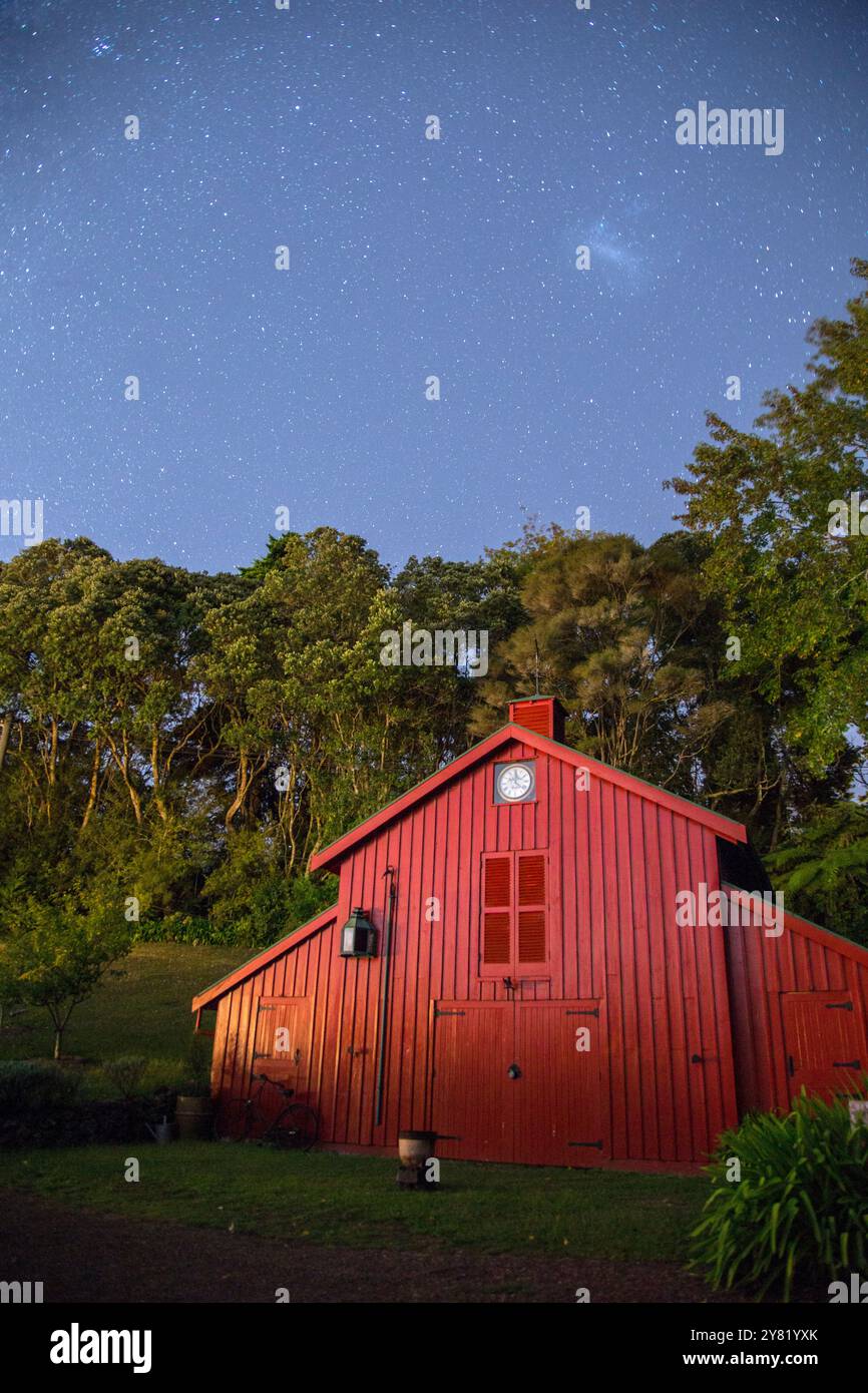 A red barn under a starry night sky surrounded by lush trees, Auckland ...