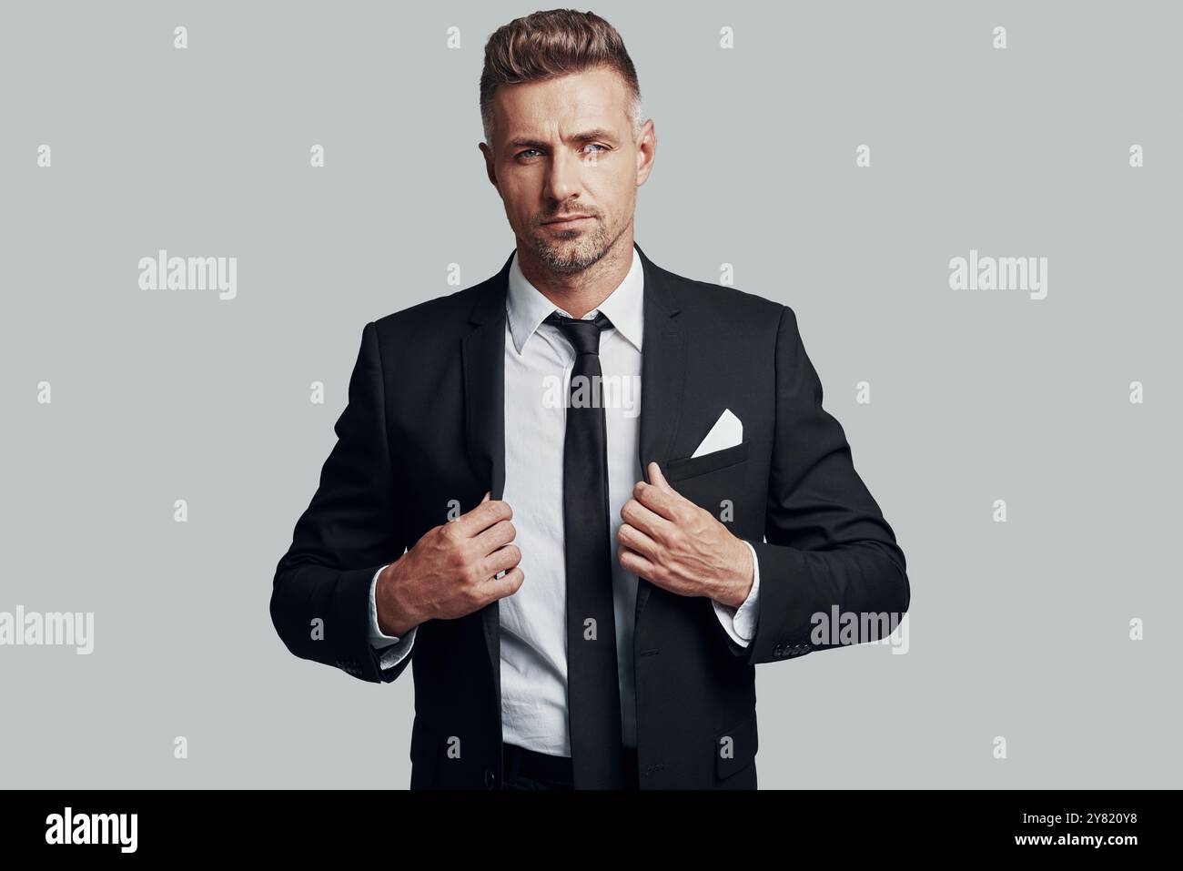 Always perfect. Handsome young man adjusting jacket and smiling while ...