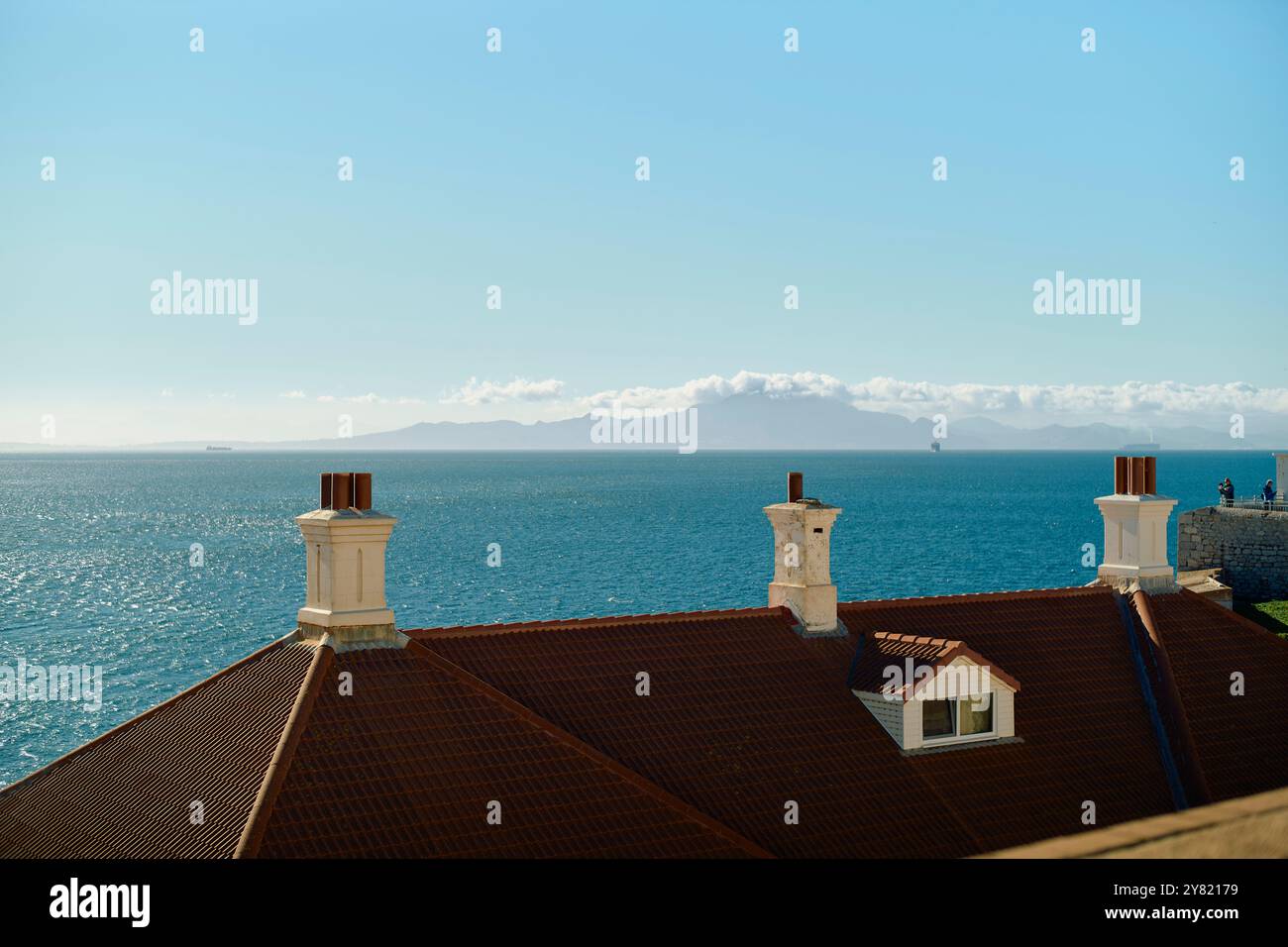 Rooftop view overlooking a calm sea with distant mountains under a ...