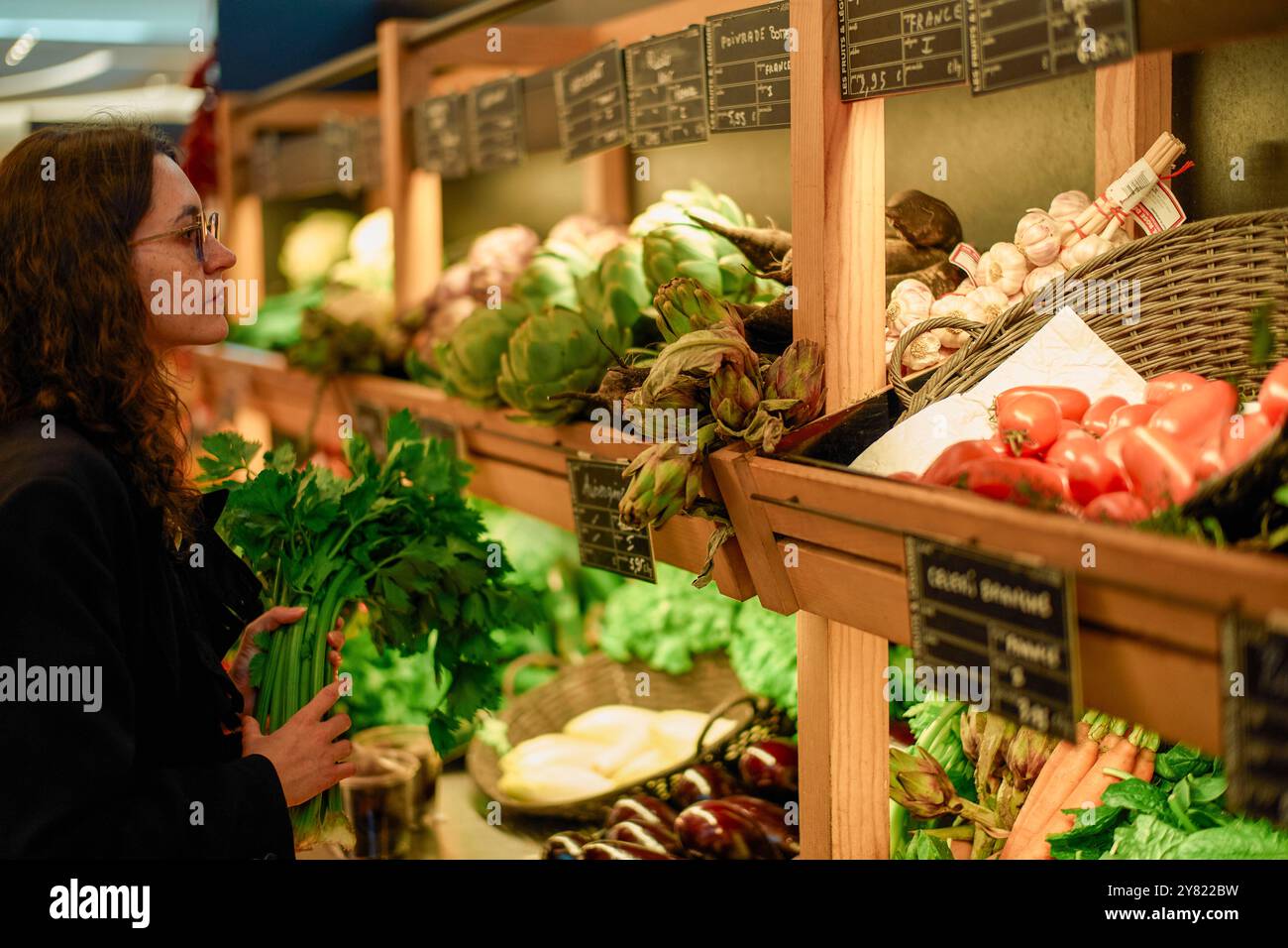 Woman shopping for vegetables at a grocery store, carefully selecting ...