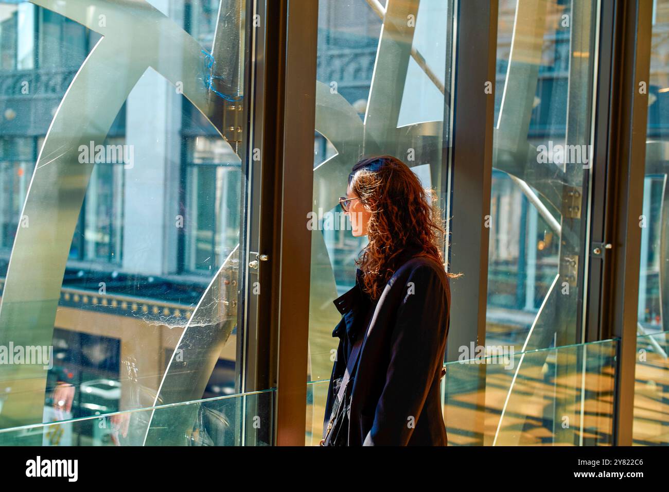 Woman in black attire standing behind a glass window with artistic ...