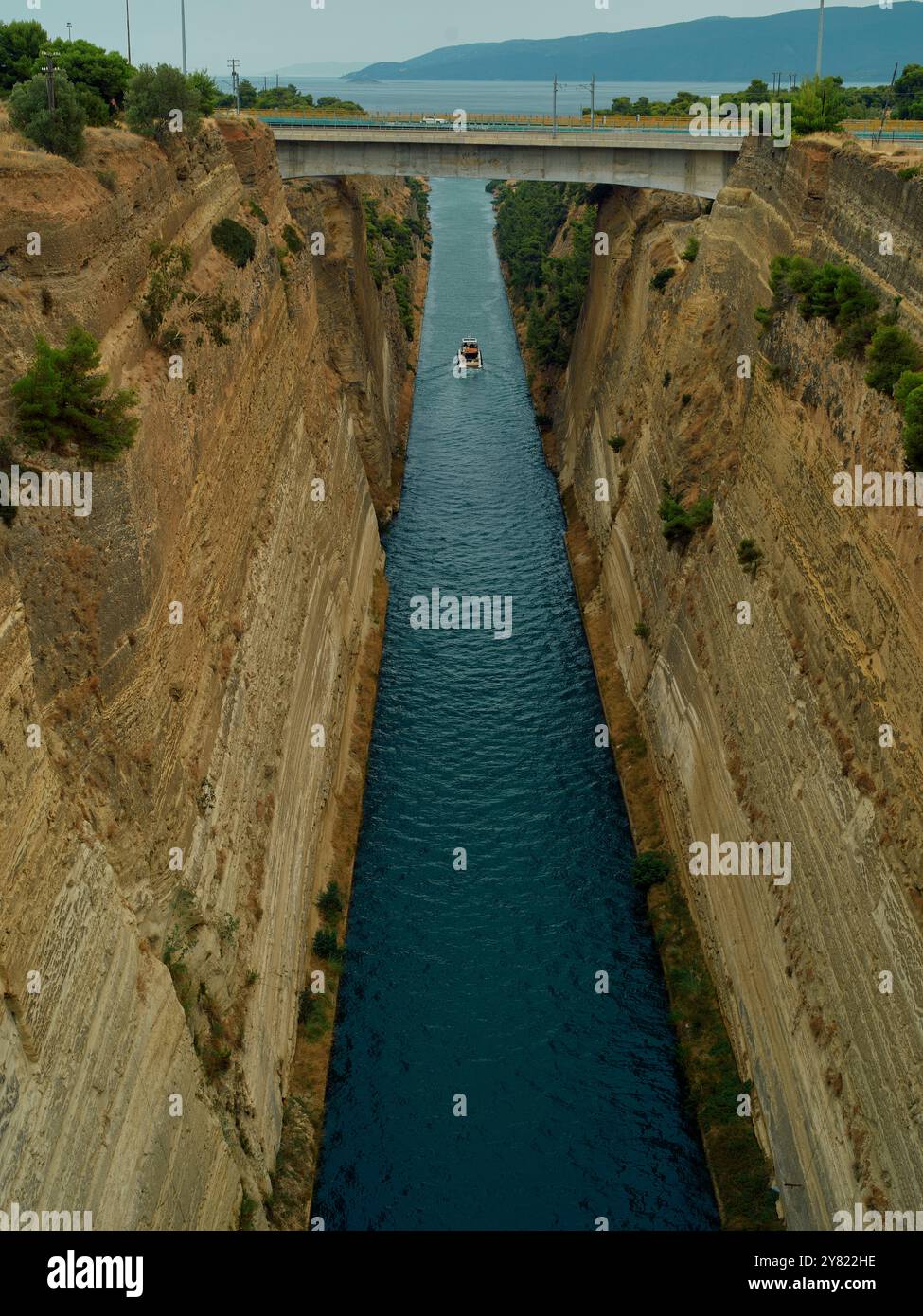 A boat sails through a narrow canal with steep rocky cliffs on either ...