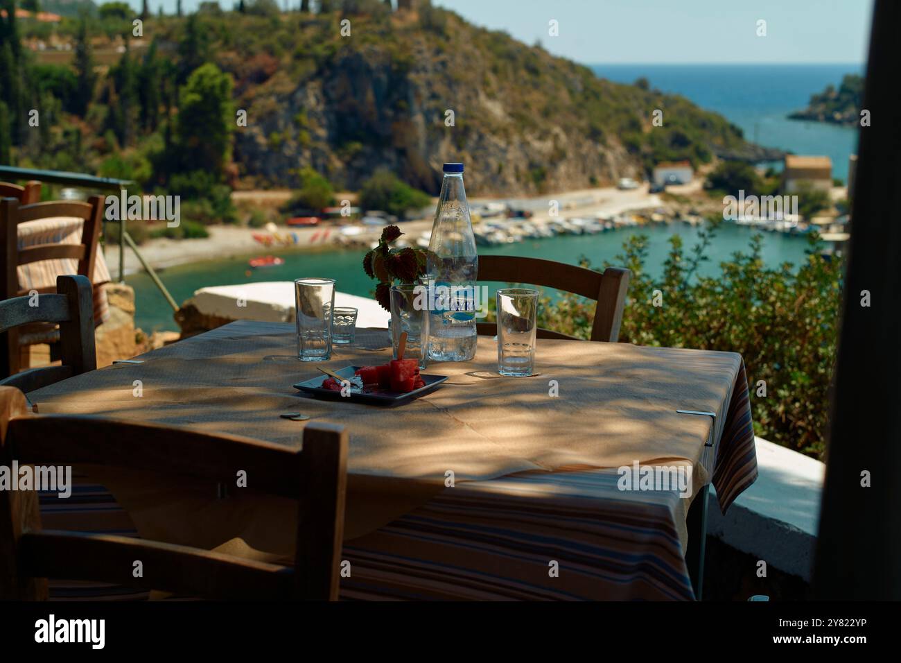 Seaside outdoor dining setup overlooking a serene cove with boats and ...